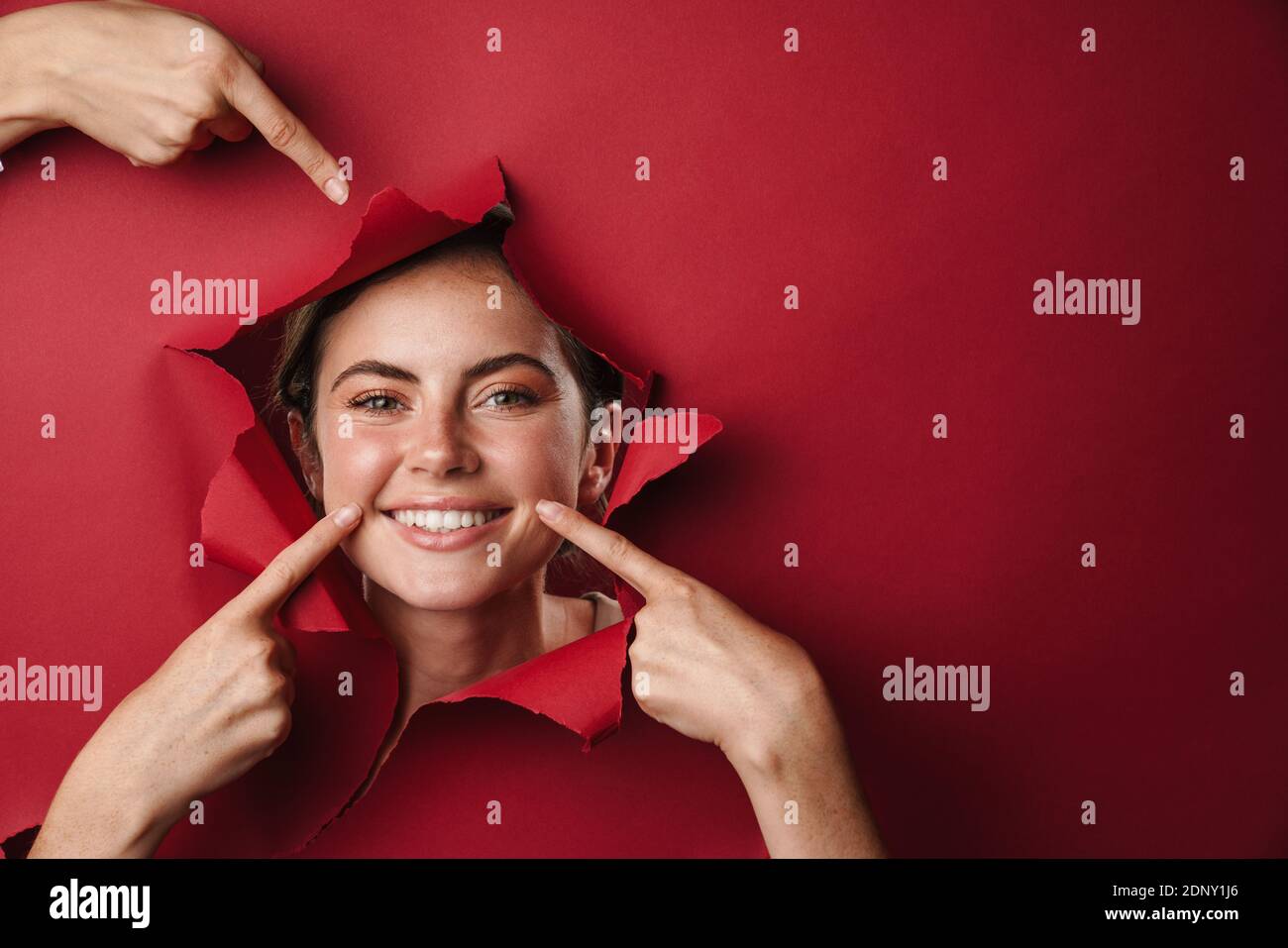 Excited girl peeping through hole in paper isolated, pointing fingers ...