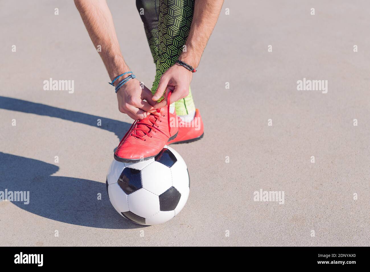 detail of a football player tying his boots with a foot on the ball in ...