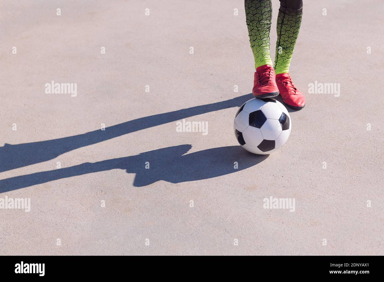 detail of a footballer feet with one foot on the ball in a concrete ...