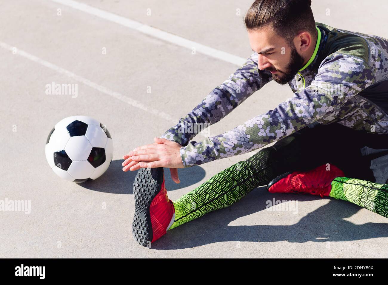 young footballer stretching legs sitting on the floor next to his ...