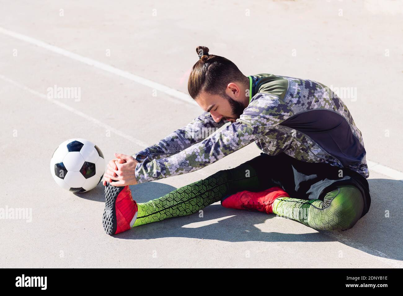football player stretching legs sitting on the floor next to his ...
