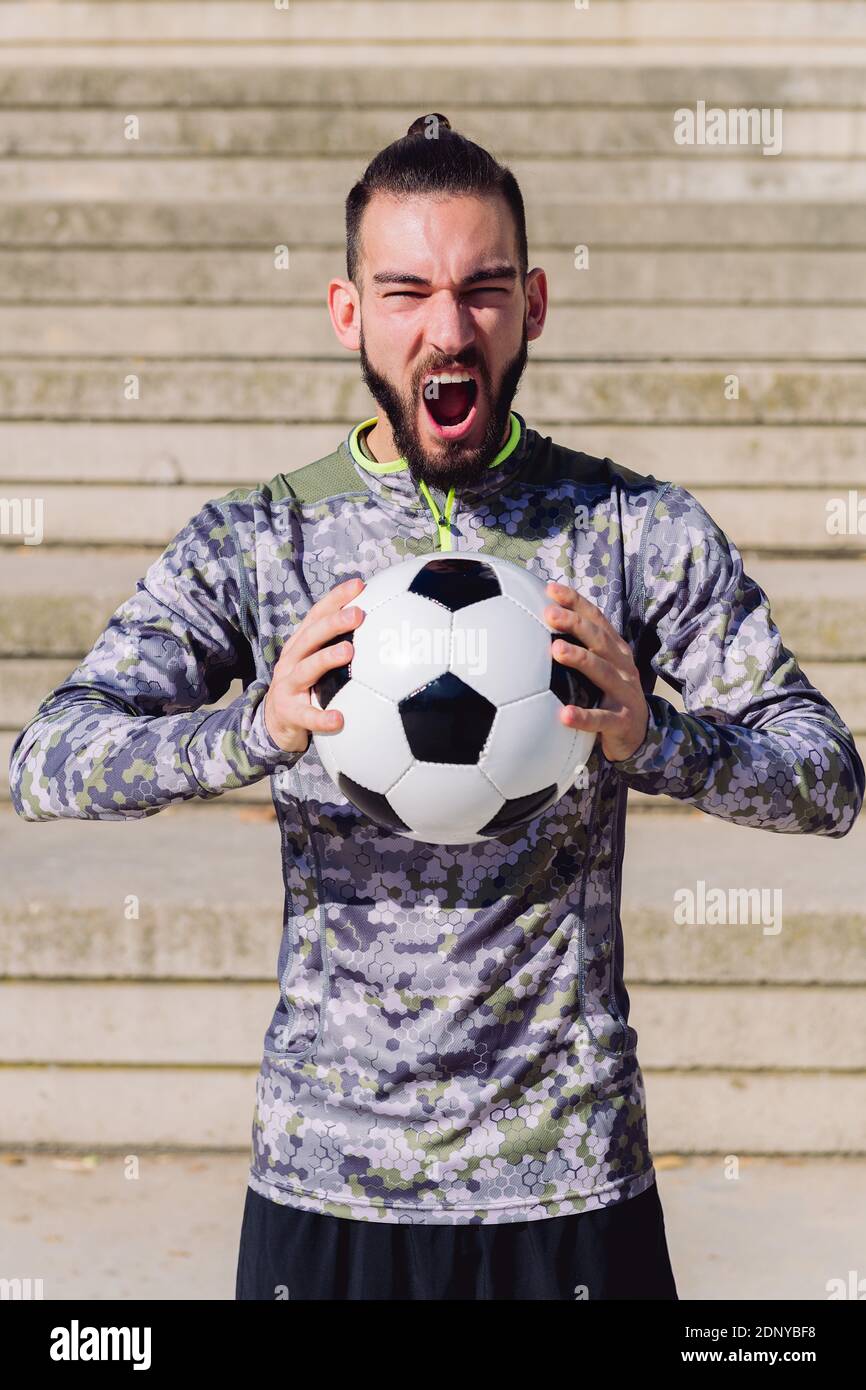 vertical portrait of a handsome sportsman screaming in a concrete ...