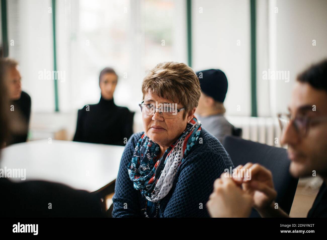 Mature woman listening during informal meeting Stock Photo - Alamy