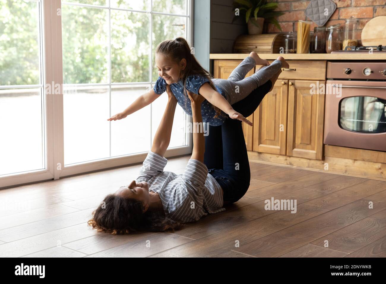 Young mom lifting little daughter up doing exercise together Stock ...