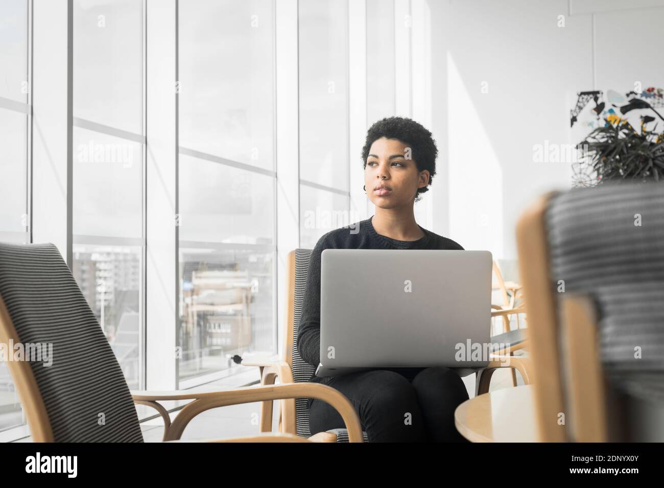 Woman with laptop on lap looking away Stock Photo - Alamy