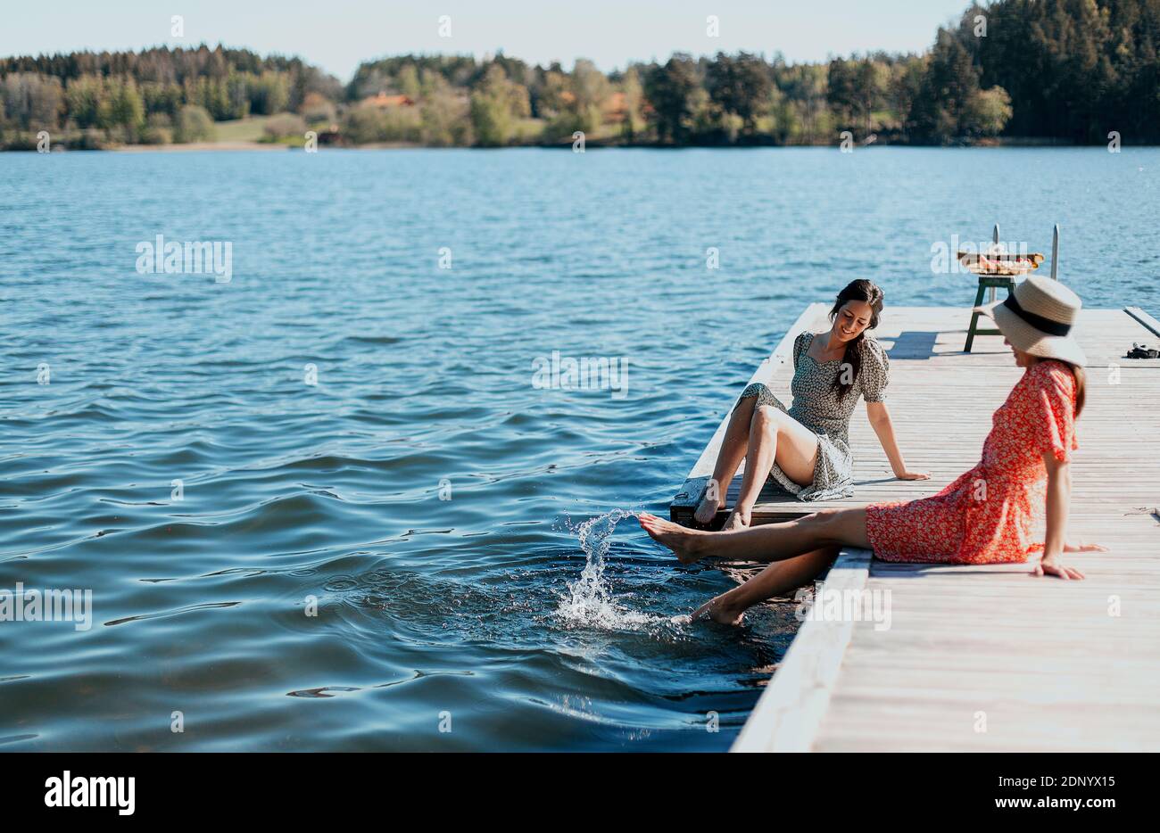 Female friends relaxing on jetty Stock Photo - Alamy