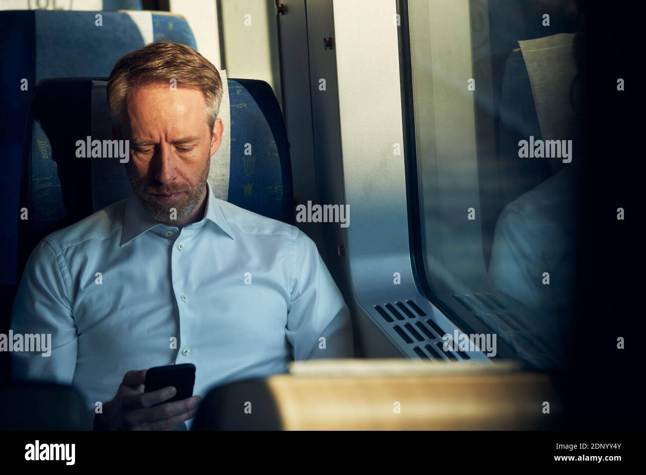 Man using cell phone in train Stock Photo - Alamy