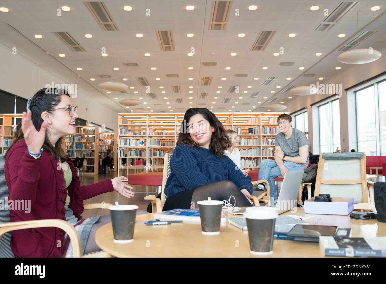 Female friends talking in library Stock Photo - Alamy