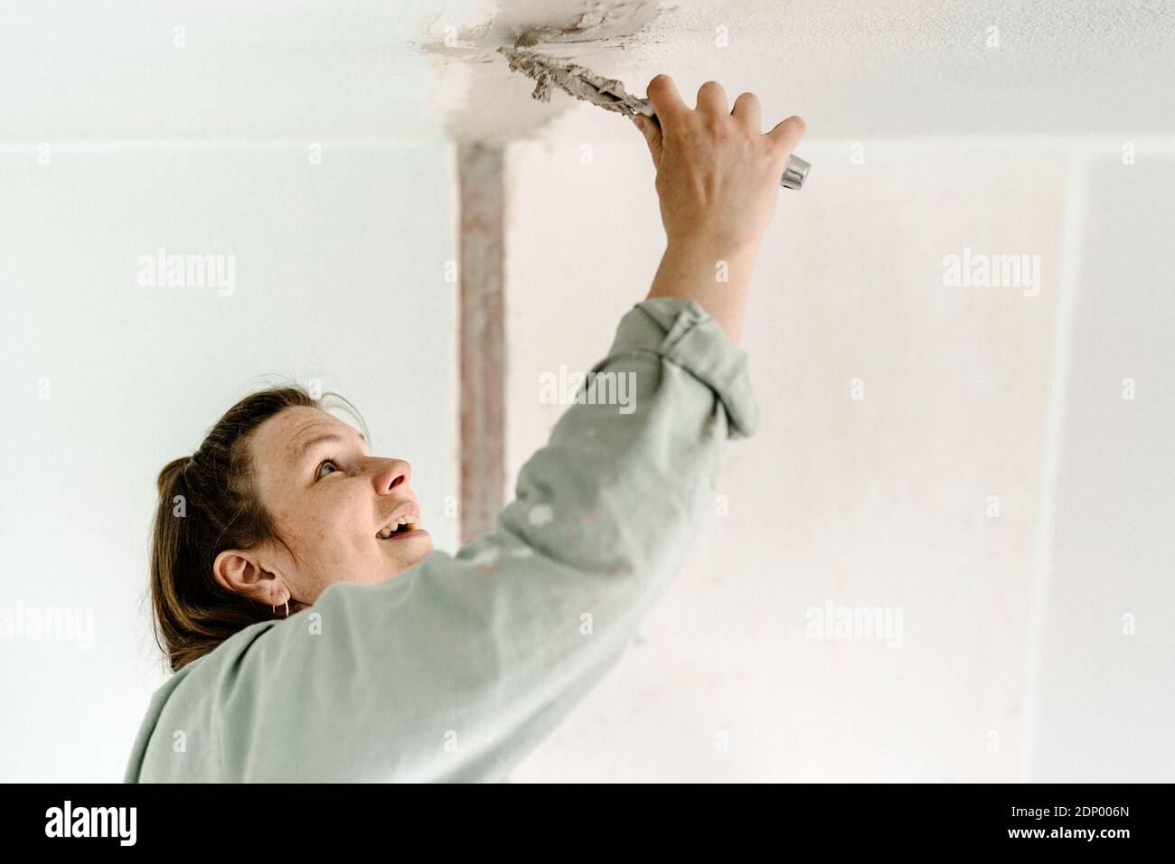 Woman putting cement on ceiling Stock Photo - Alamy