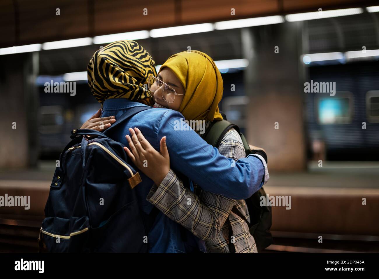 Female friends hugging on train station platform Stock Photo - Alamy