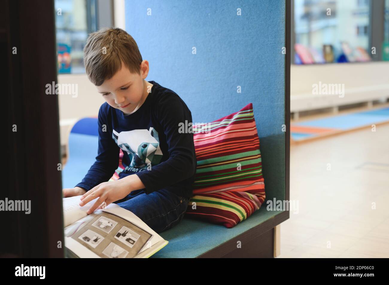 Boy reading book in library Stock Photo - Alamy