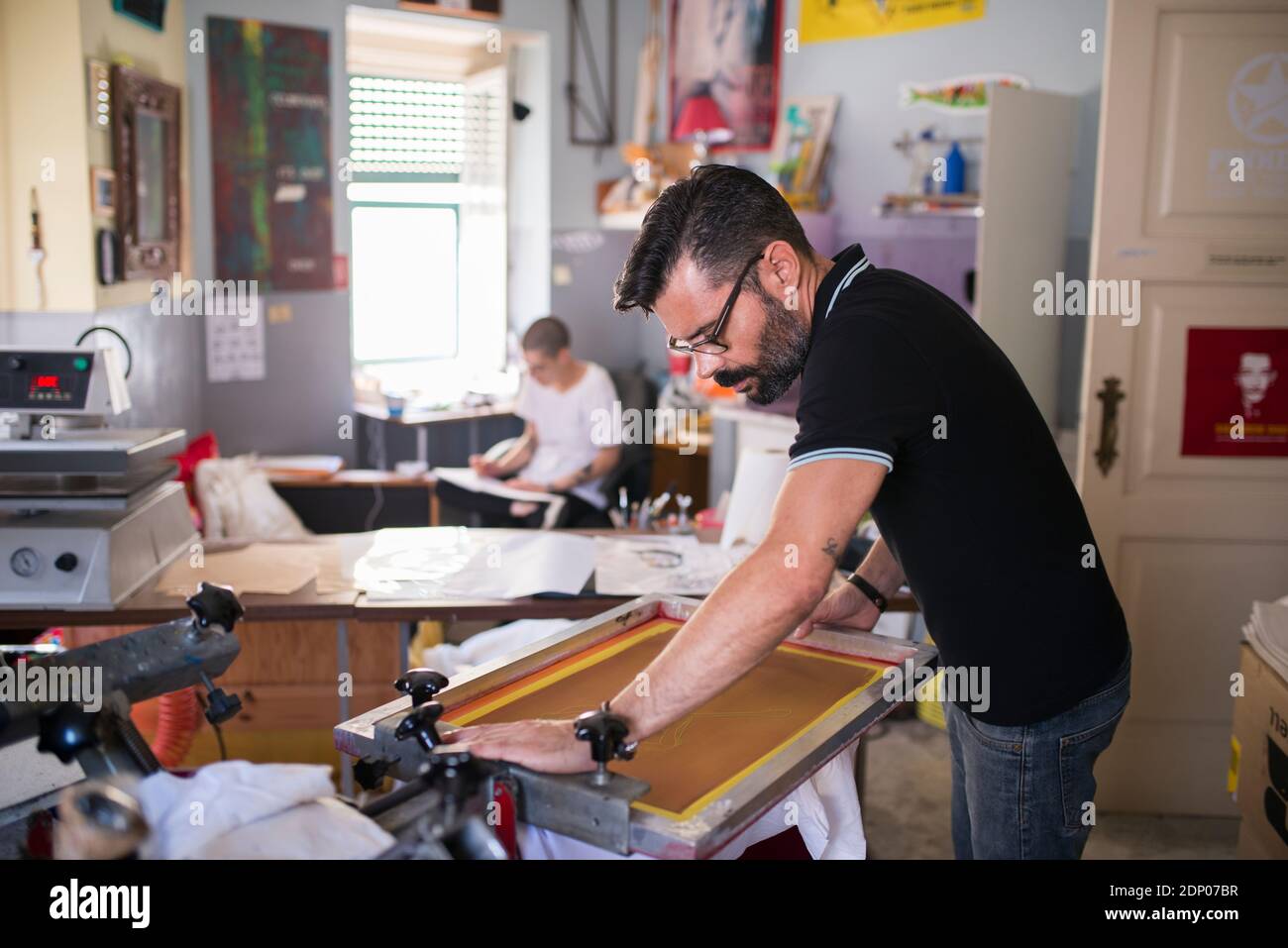 Man operating screen printing equipment Stock Photo - Alamy