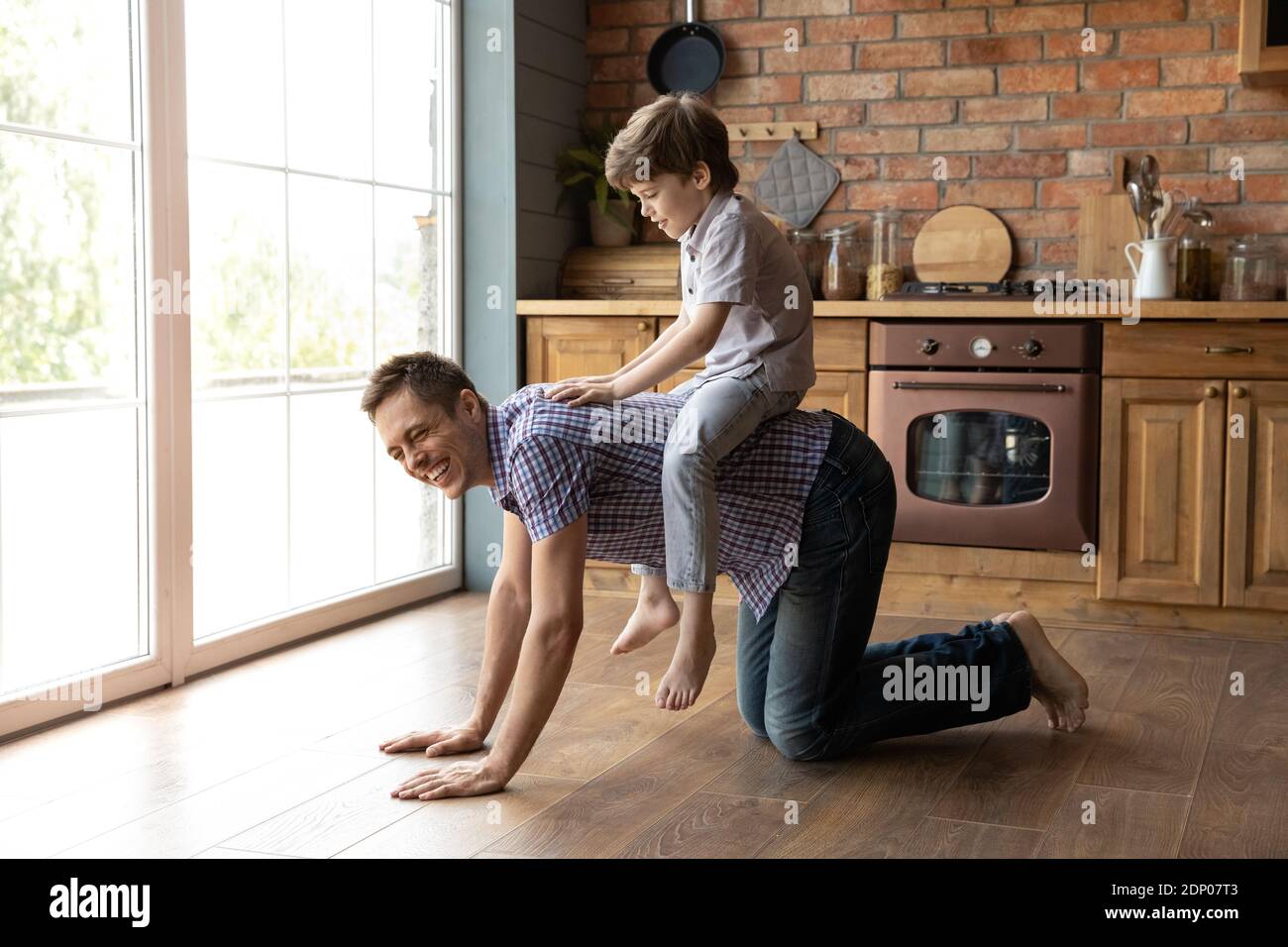 Young dad crawling by warm floor holding son on back Stock Photo - Alamy