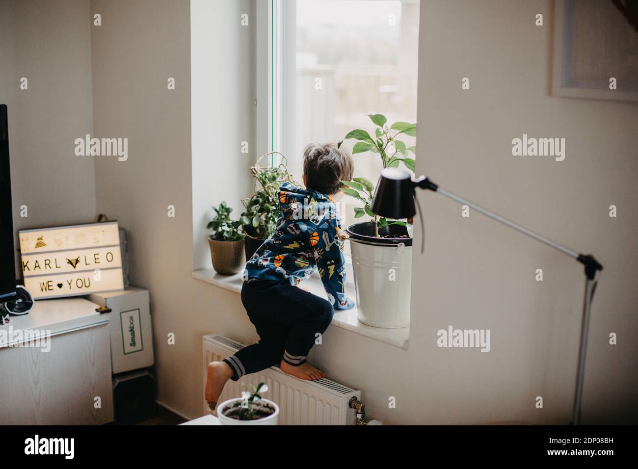 Boy looking through window Stock Photo - Alamy