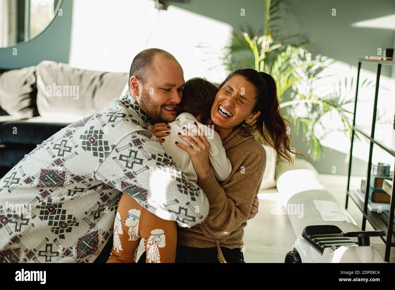 Happy parents hugging child Stock Photo - Alamy
