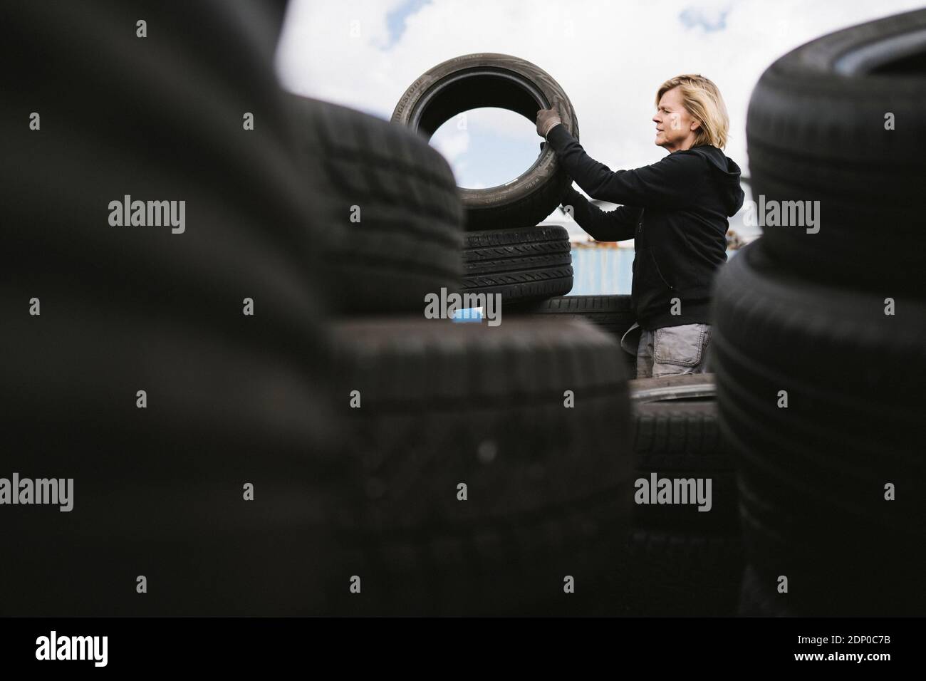 Female mechanic stacking car tires Stock Photo - Alamy