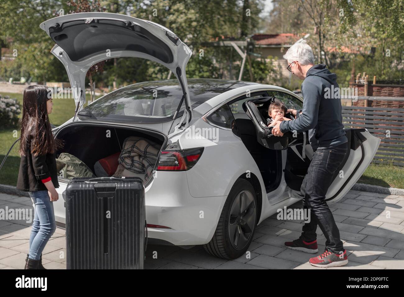 Man putting daughter into car Stock Photo - Alamy