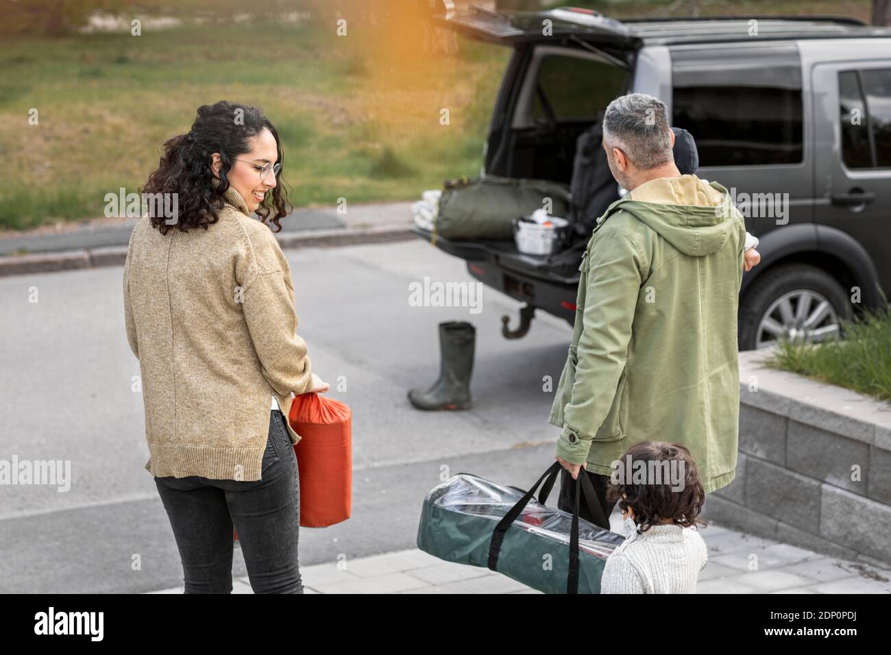 Parents with toddler walking towards car Stock Photo - Alamy