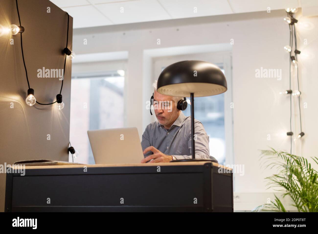 Man wearing headset working in office Stock Photo - Alamy