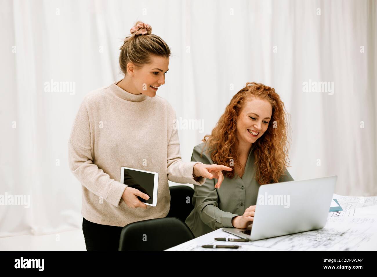 Female coworkers talking in office Stock Photo - Alamy