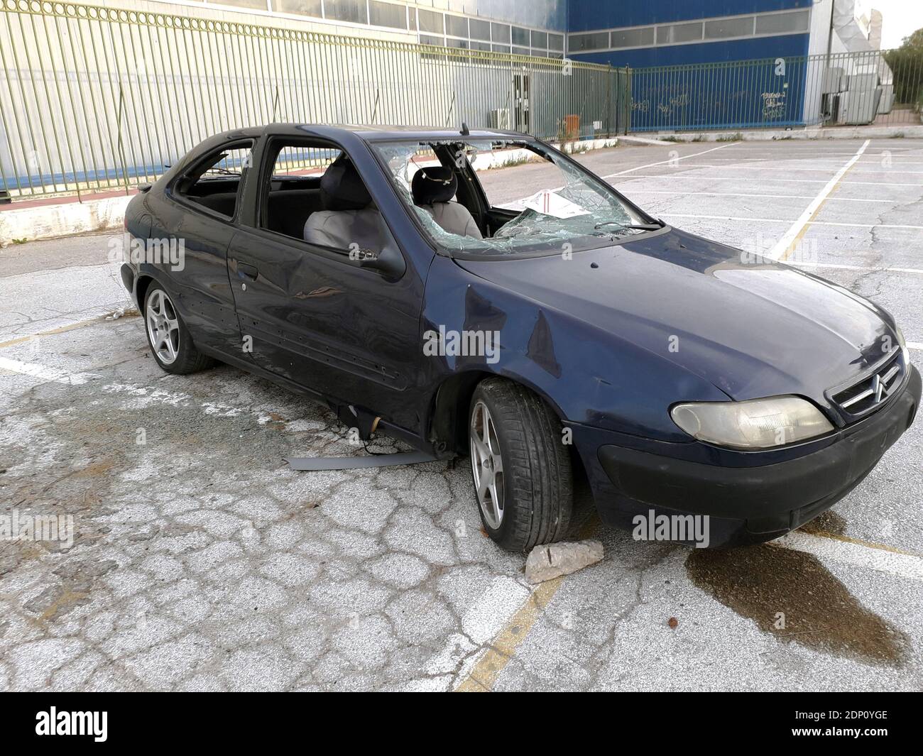 Vandalized blue car with broken windows and a wheel missing Stock Photo ...