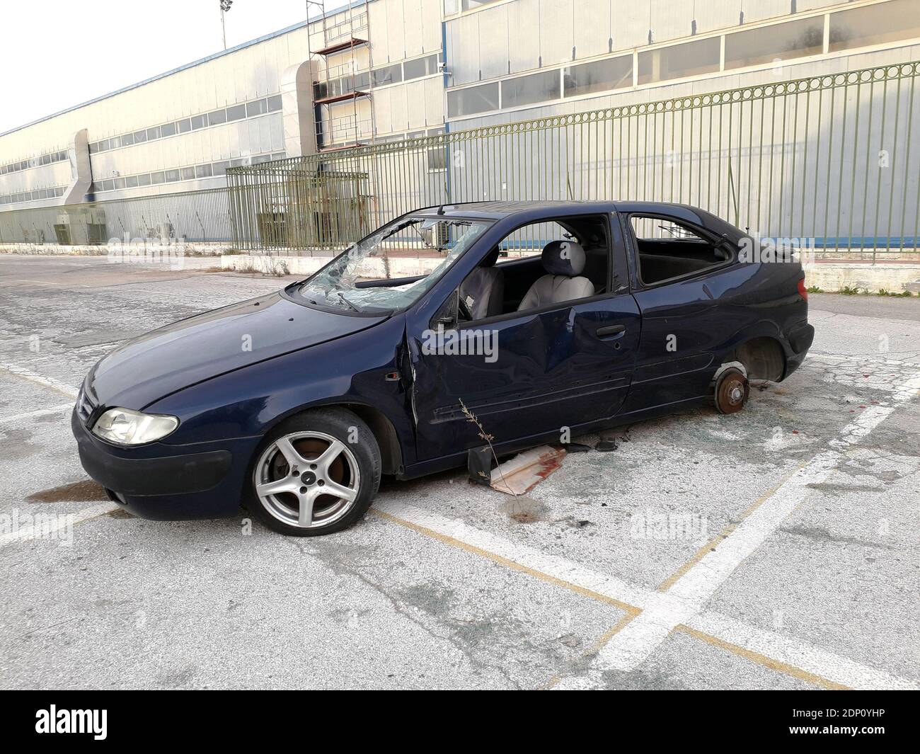 Vandalized blue car with broken windows and a wheel missing Stock Photo ...