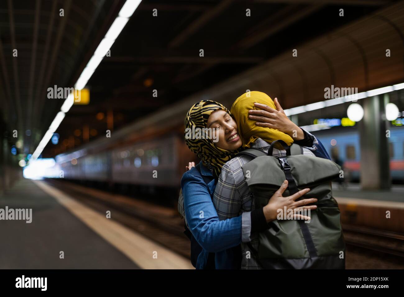 Female friends hugging on train station platform Stock Photo - Alamy