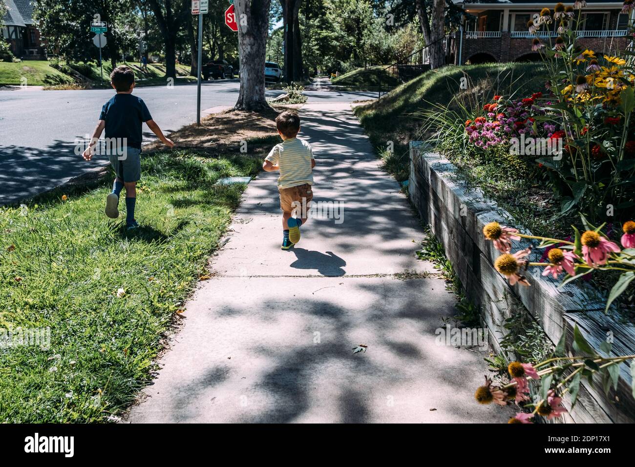 Two young boys running on a sidewalk in neighborhood Stock Photo - Alamy