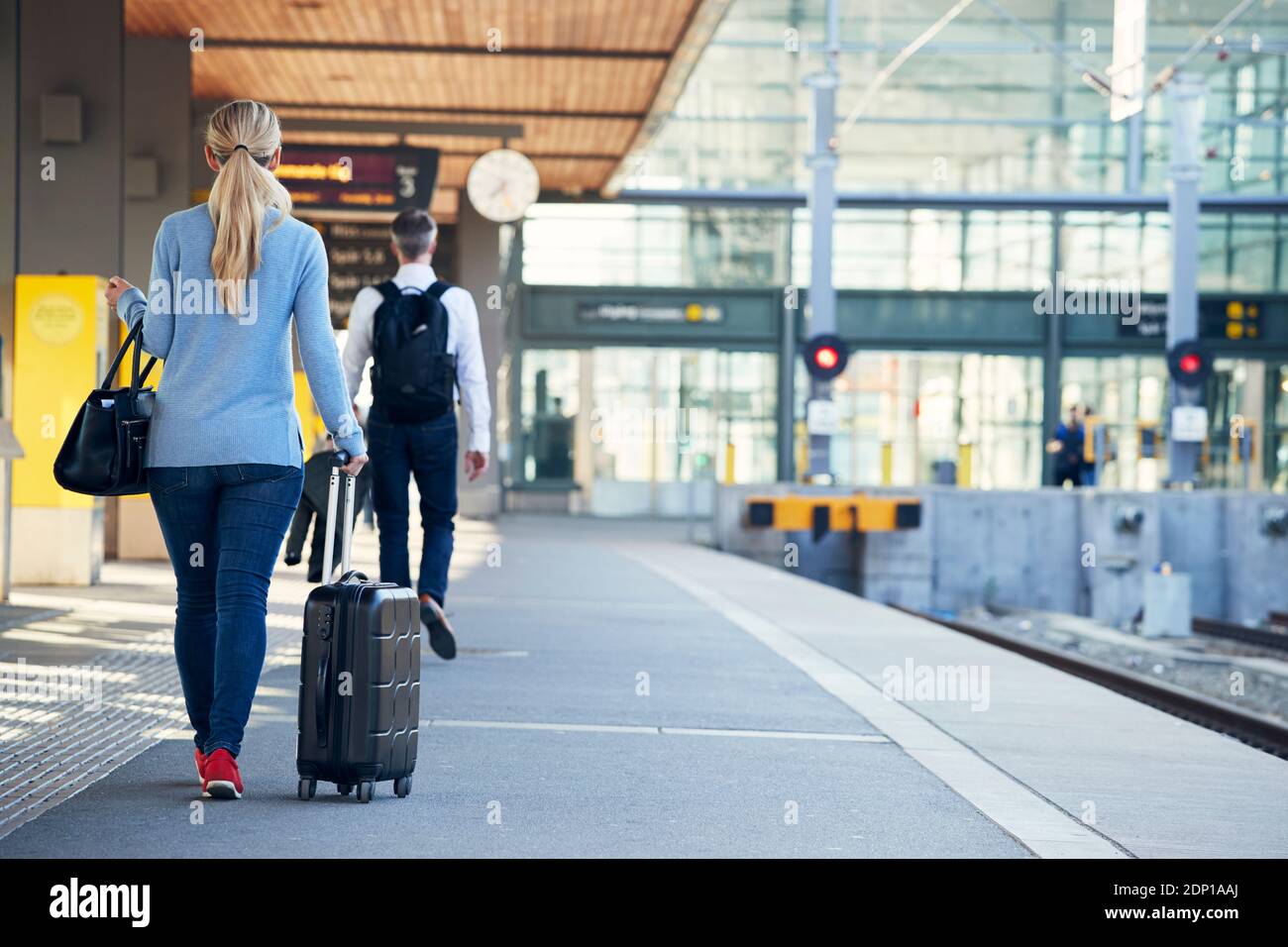 Rear view of woman walking on train station platform Stock Photo - Alamy