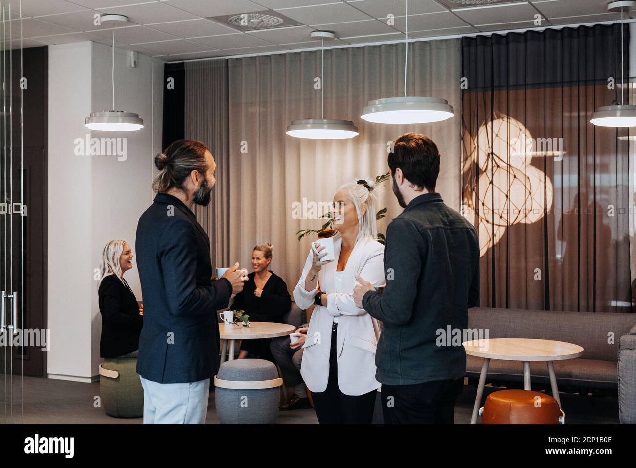 Coworkers talking on corridor Stock Photo - Alamy