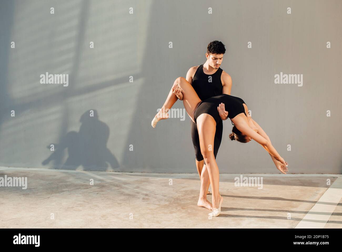 Professional male dancer helping female gymnast in dance pose against ...