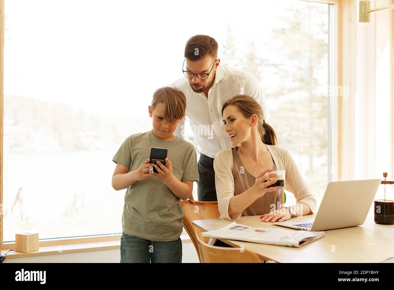 Boy using cell phone while parents watching Stock Photo - Alamy