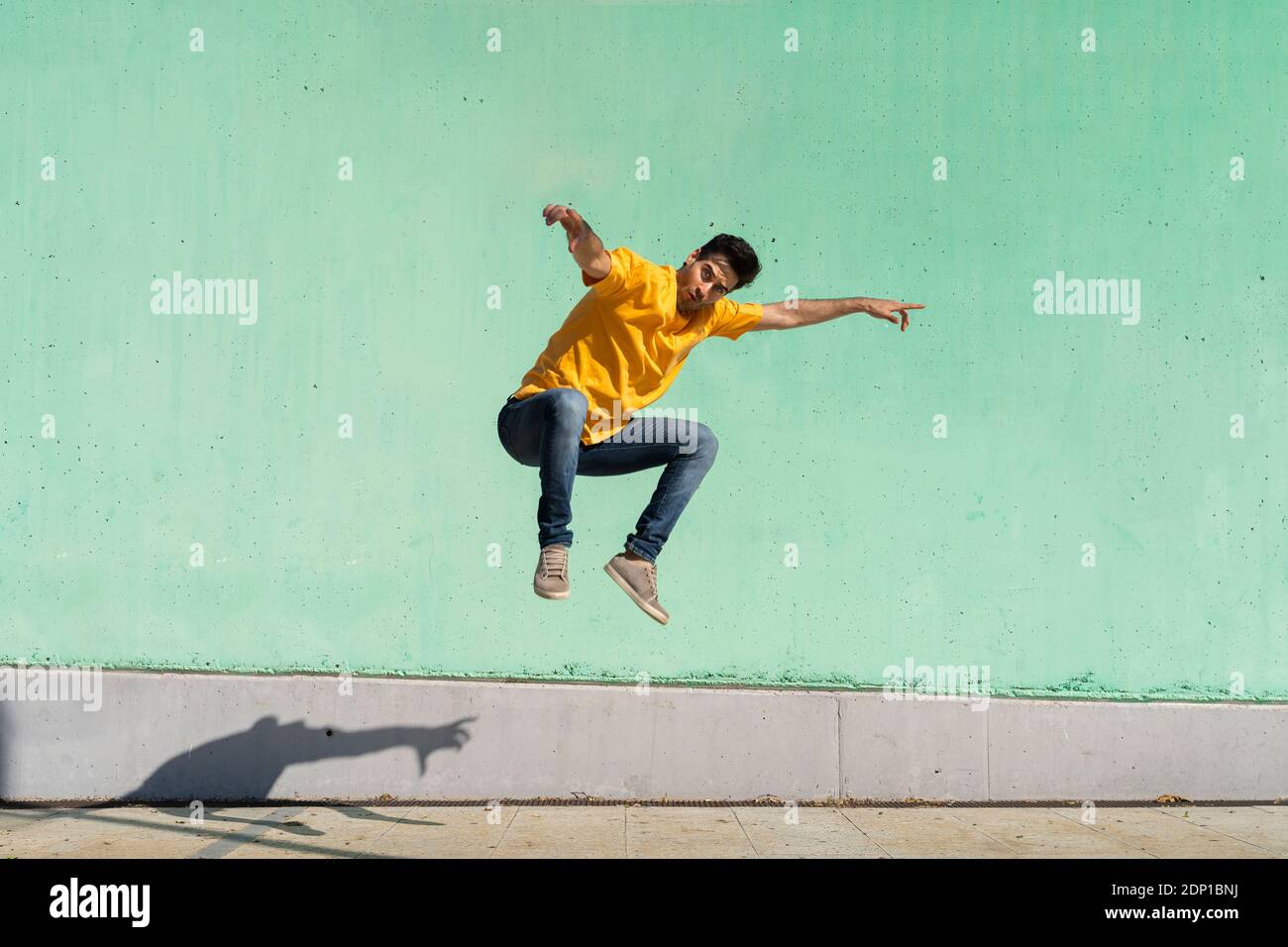 Casual man jumping in front of colorful wall Stock Photo - Alamy