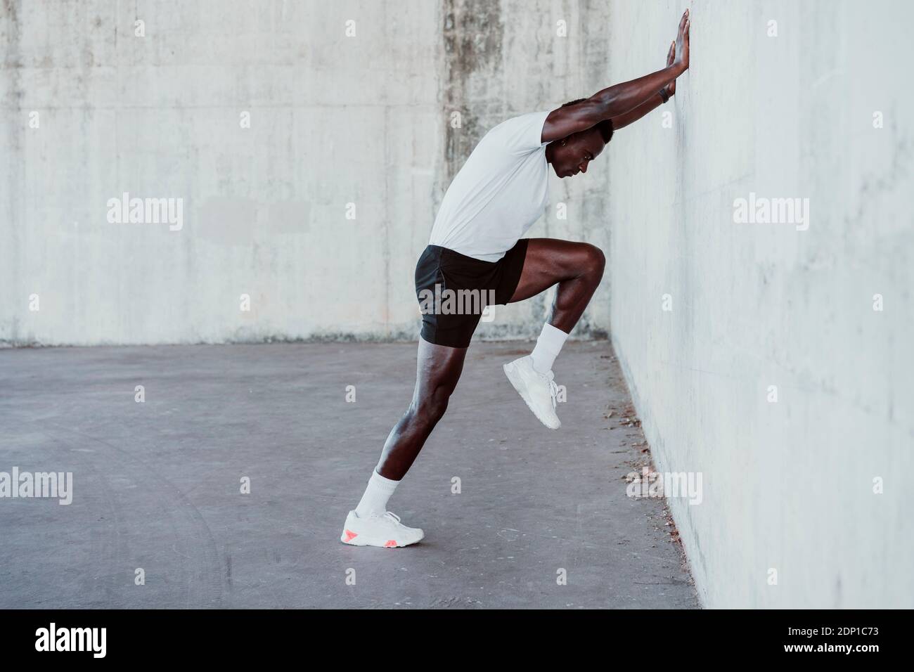Sportsman doing stretching workout while leaning on white wall Stock ...