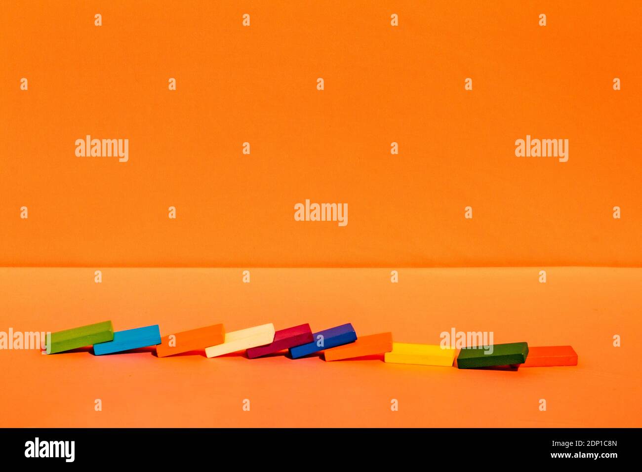 Multi colored construction blocks fallen on orange background Stock ...