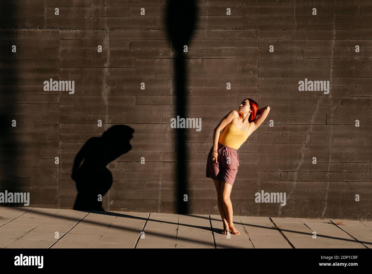 Woman dancing barefoot with black urban wall background and her shadow ...