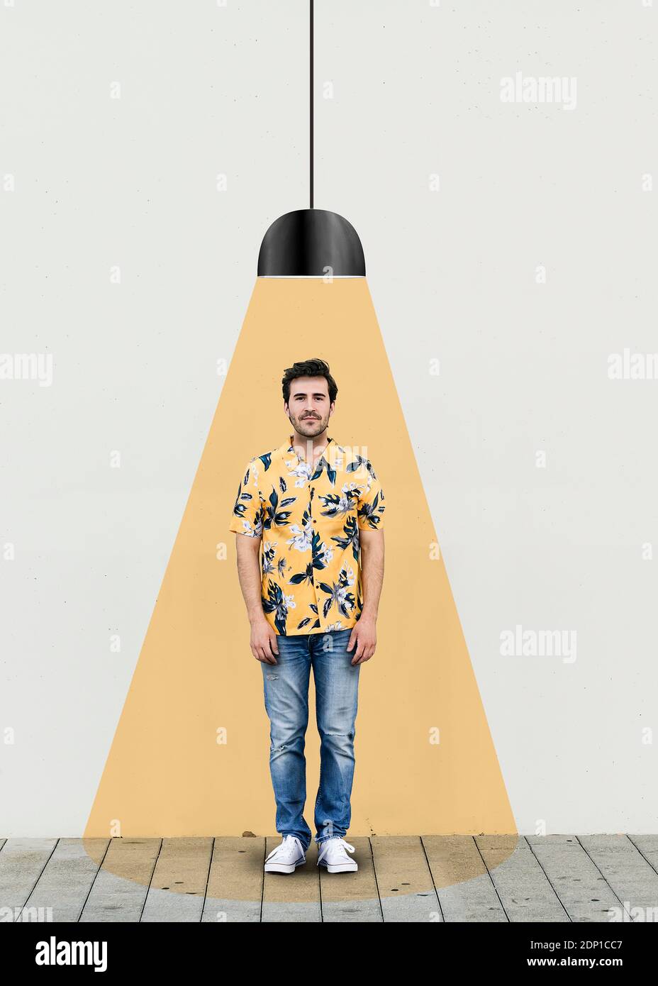 Young man standing under illuminated light against wall Stock Photo - Alamy