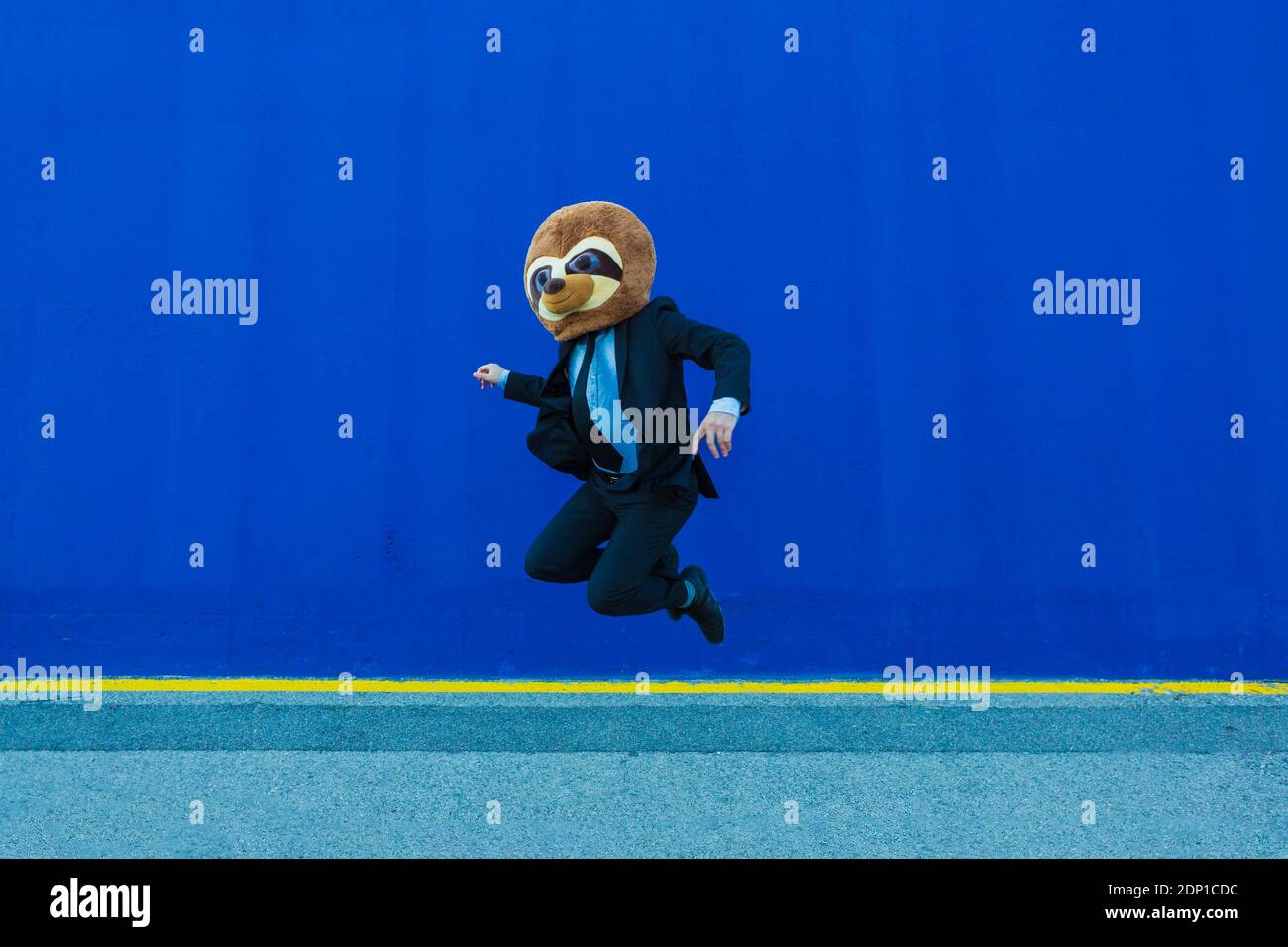 Businessman in black suit with meerkat mask jumping in the air in front ...