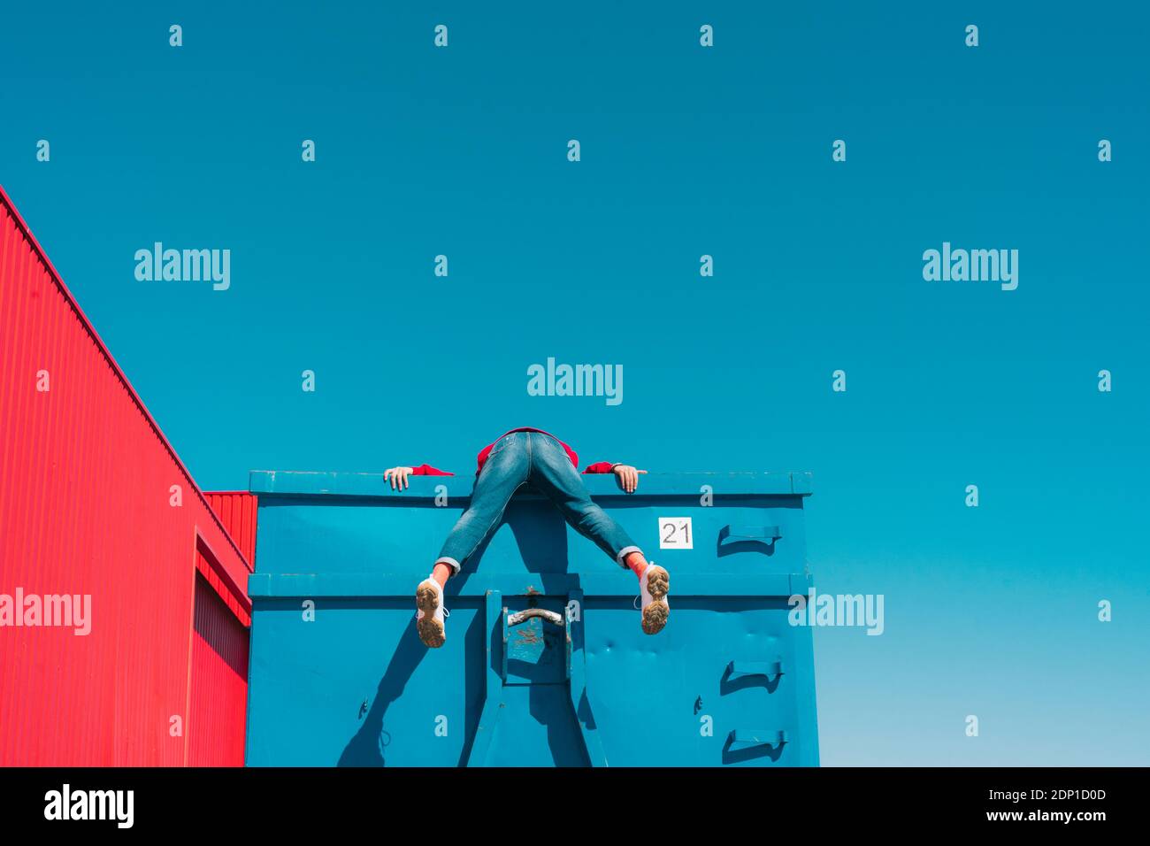 Young man hanging over edge of blue container, rear view Stock Photo ...