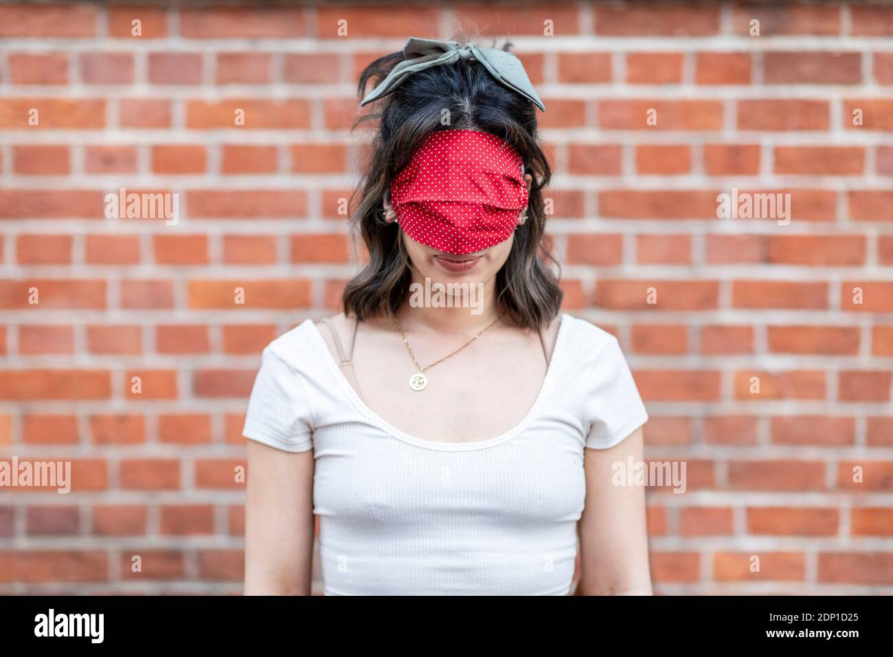 Close-up of young woman's face covered with red mask standing against ...
