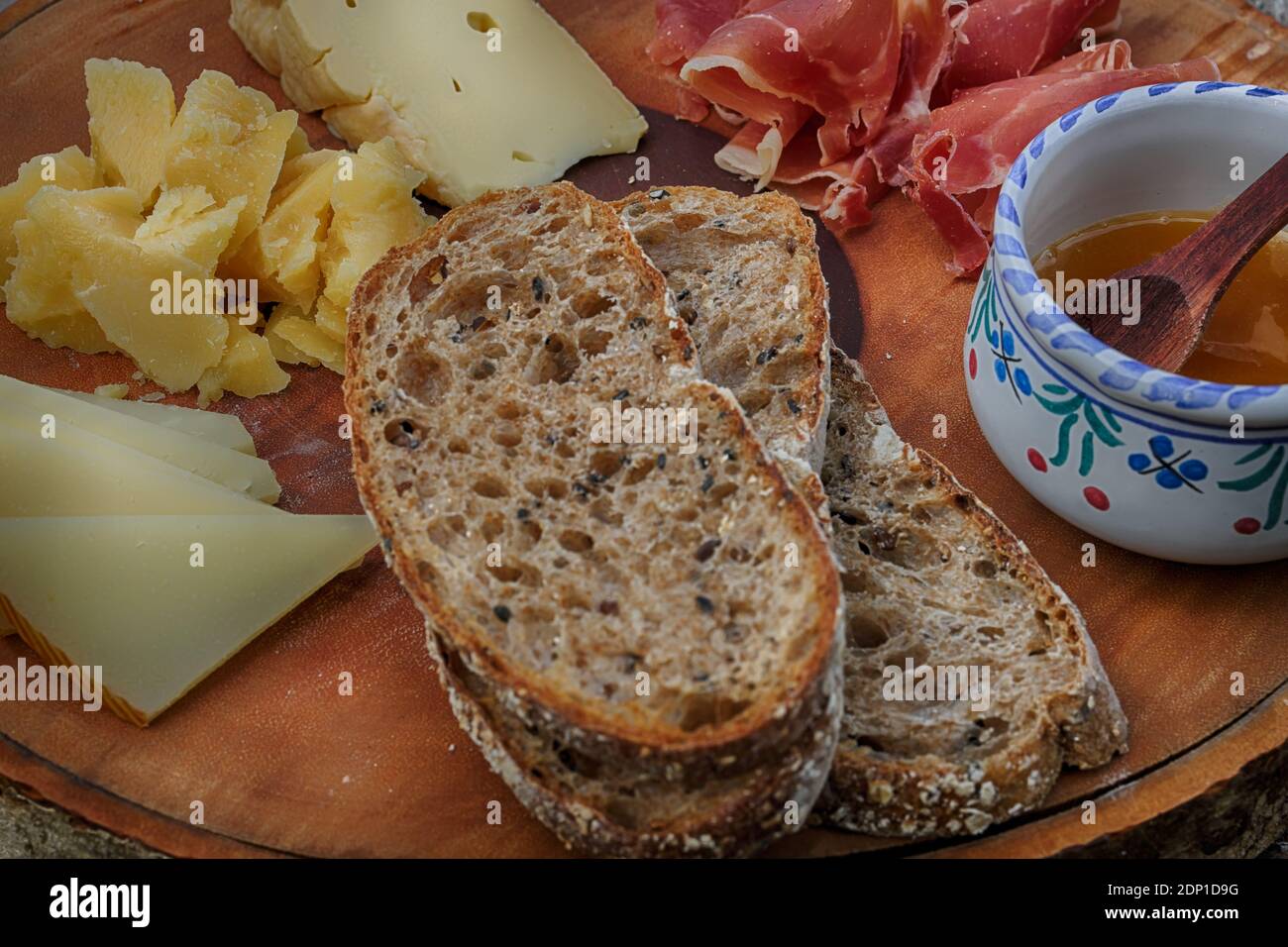 Wood table of cheese, ham, bread slides and honey Stock Photo - Alamy