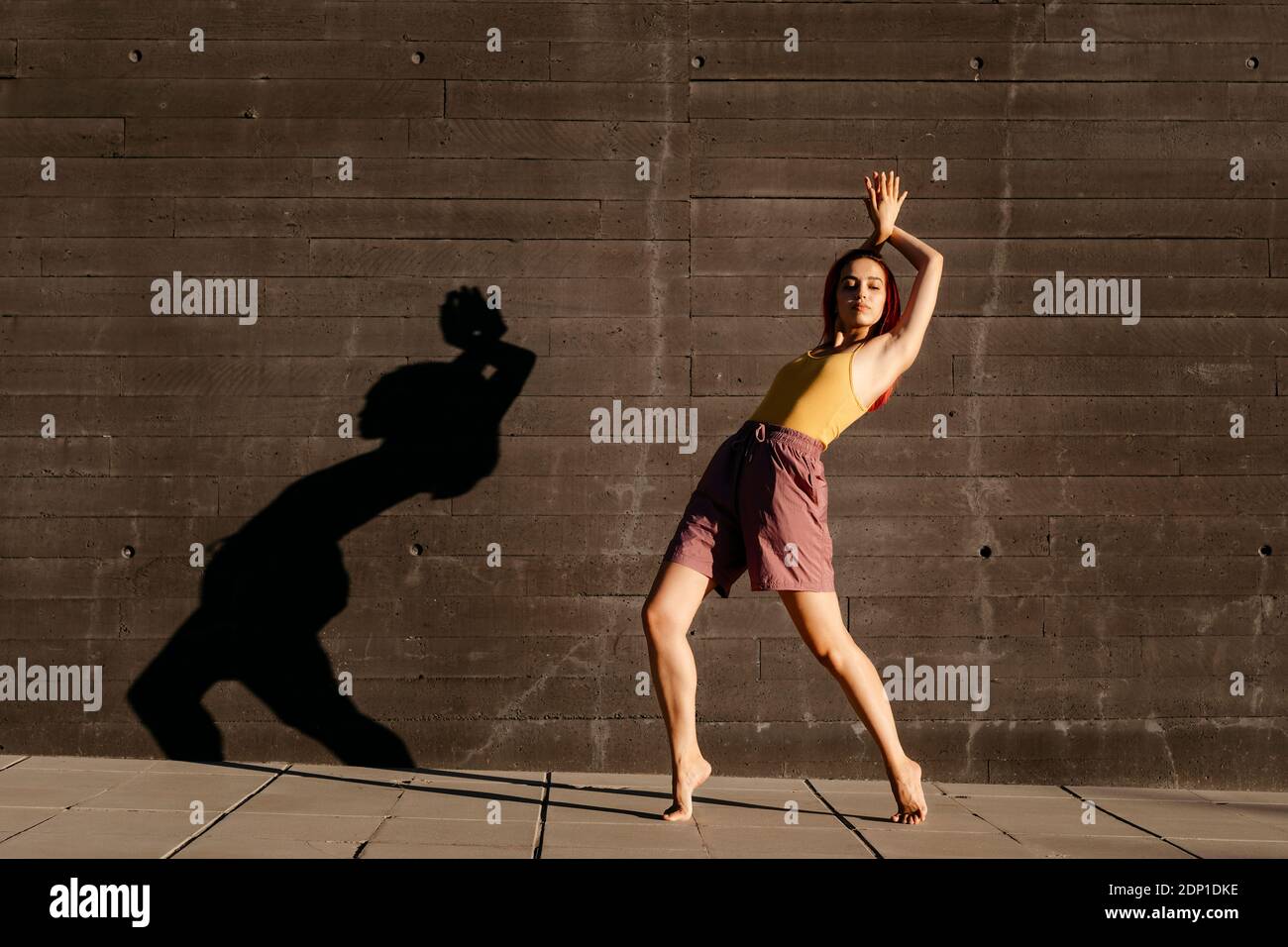 Woman dancing barefoot with black urban wall background and her shadow ...