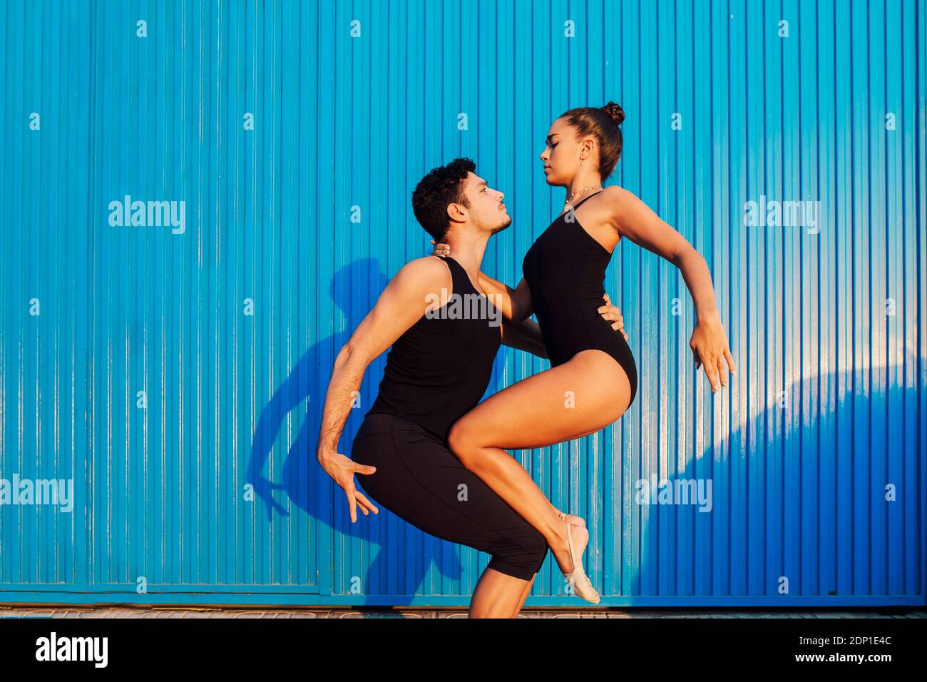 Professional gymnast couple doing balancing pose by blue corrugated ...