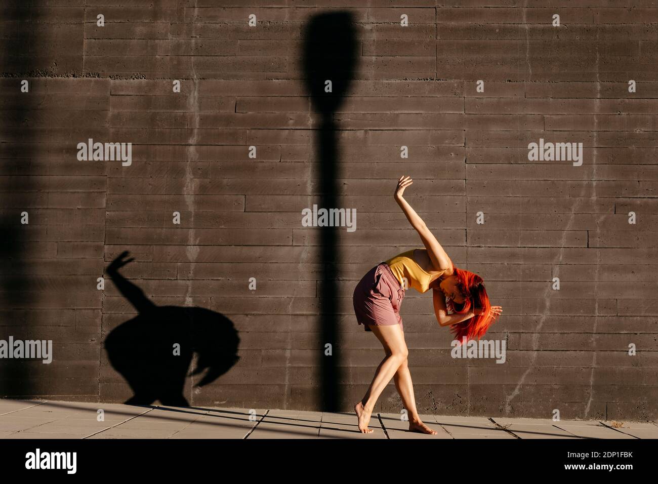 Woman dancing barefoot with black urban wall background and her shadow ...