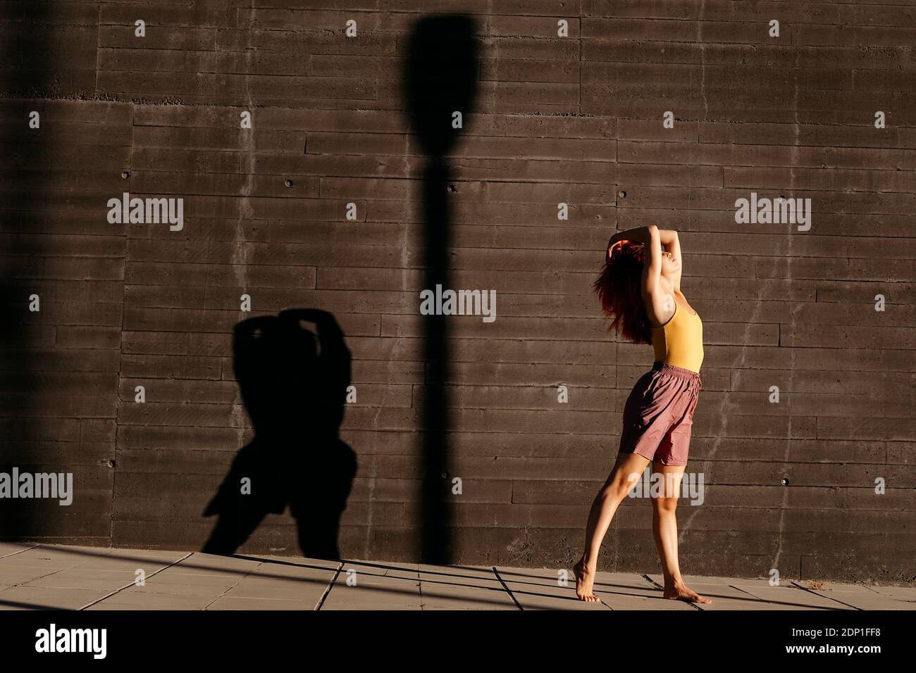 Woman dancing barefoot with black urban wall background and her shadow ...