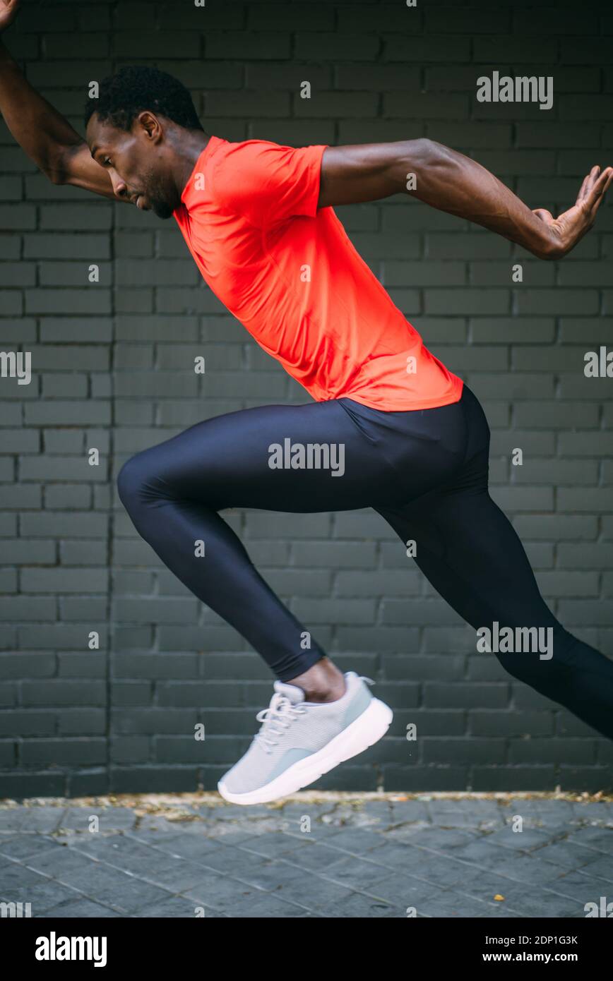 Young sportive man jumping in front of a brick wall Stock Photo - Alamy