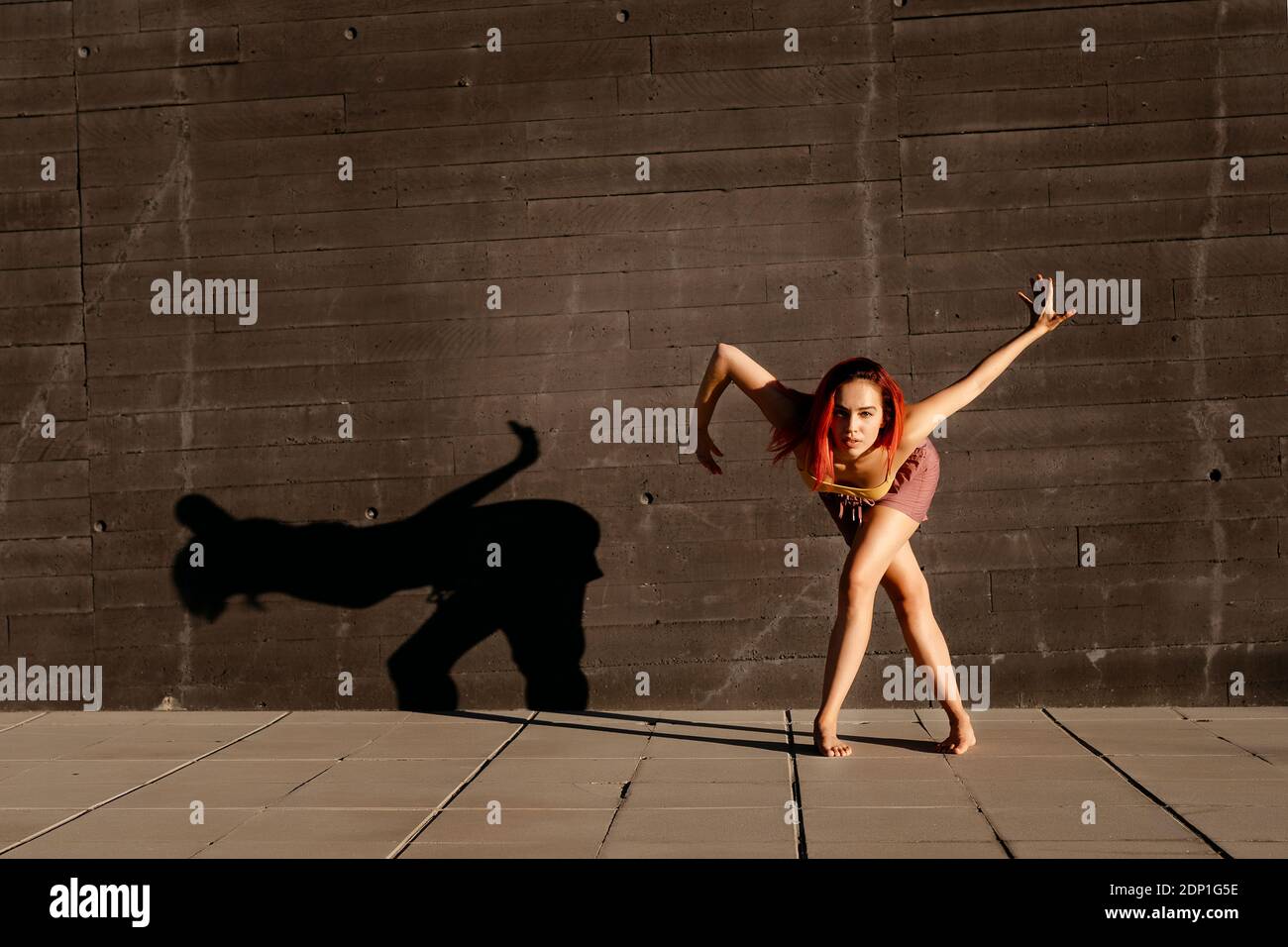 Woman dancing barefoot with black urban wall background and her shadow ...