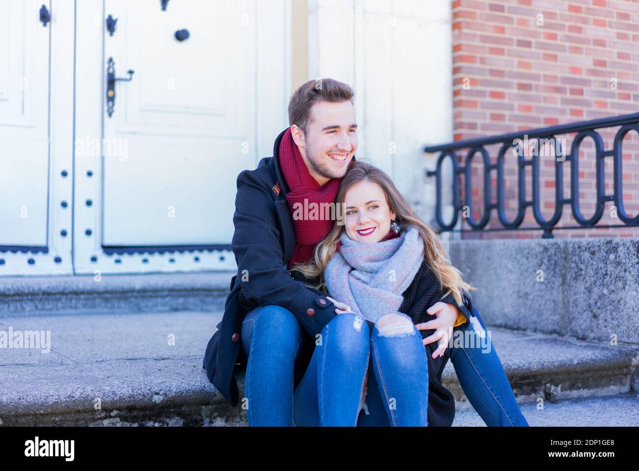 Portrait of smiling young couple hugging sitting on the stairs on ...