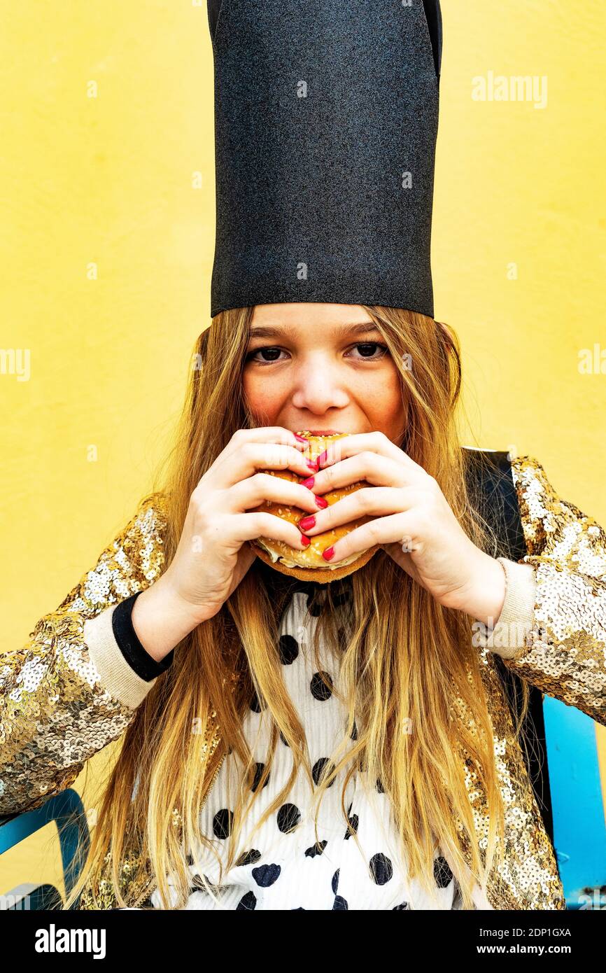 Portrait of girl wearing black crown eating Hamburger Stock Photo - Alamy
