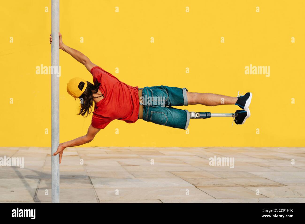 Young athlete holding pole while balancing body weight against multi ...
